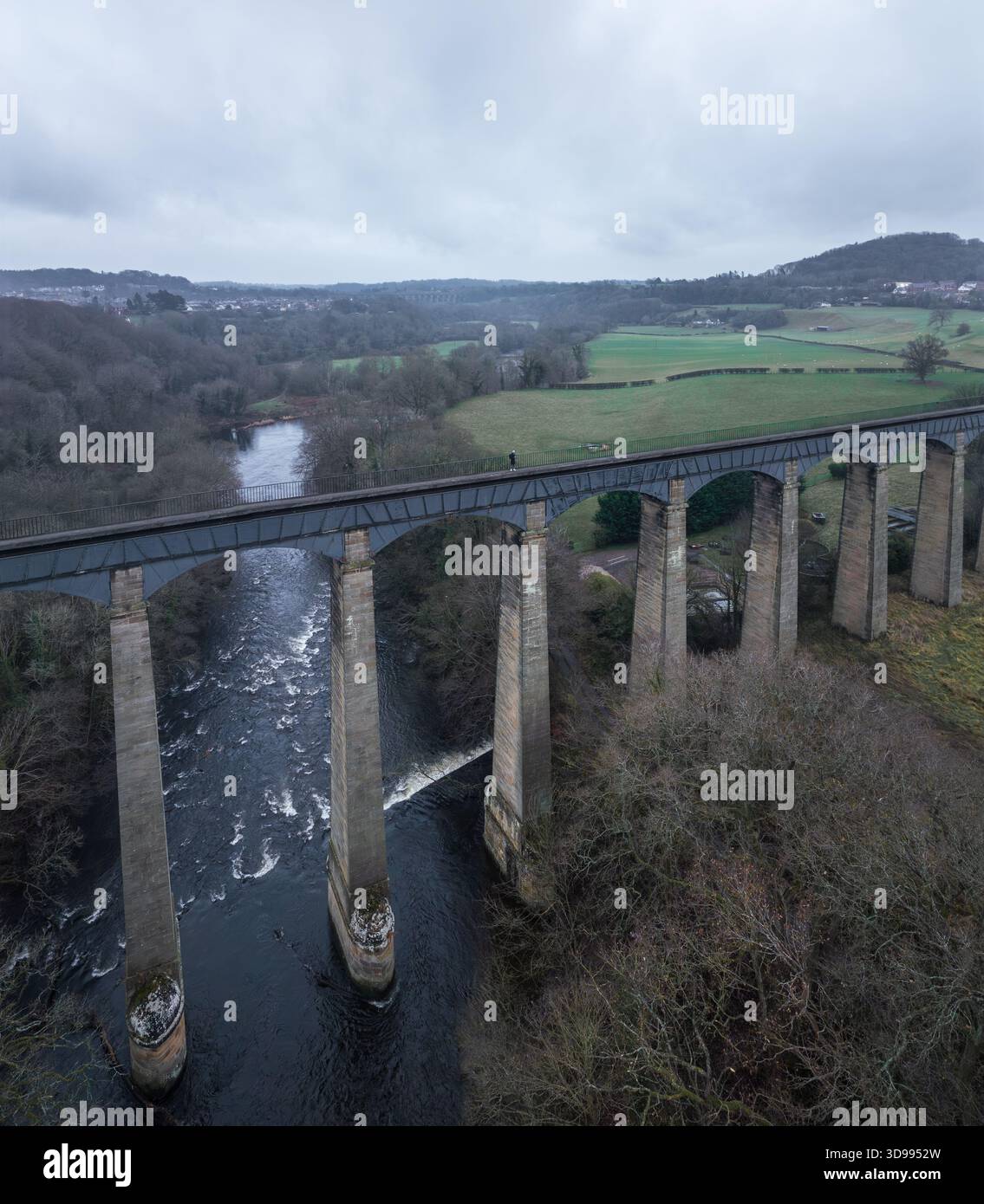 Aerial view of the dark waters flow under the stark grey arches of a ...