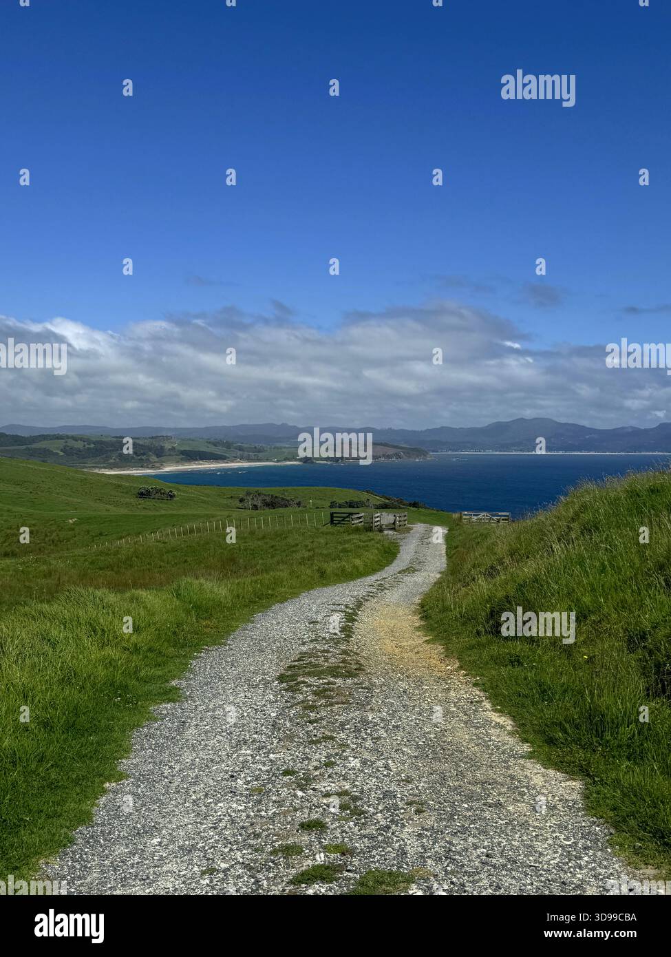 Coastal view with narrow road, sea, beach and mountains beyond ...