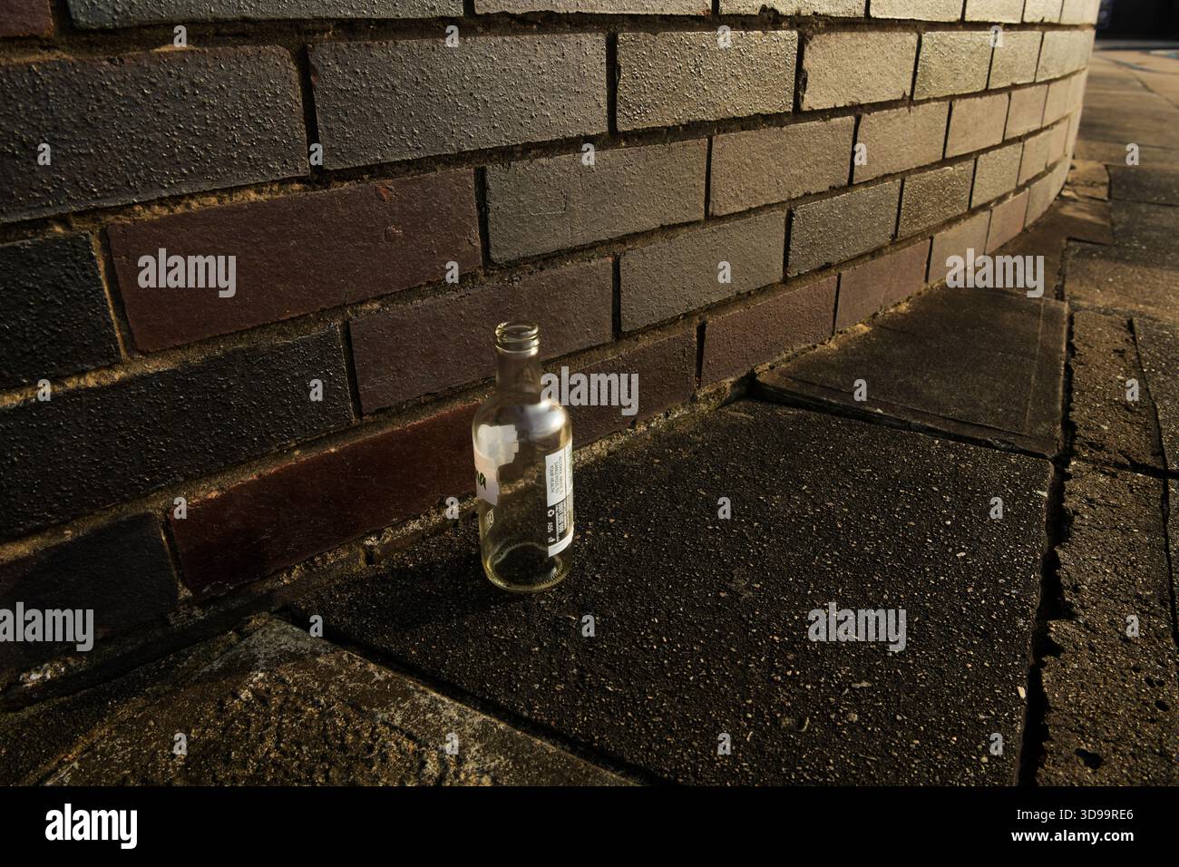 Empty glass alcoholic beverage bottle left next to wall after drinking ...