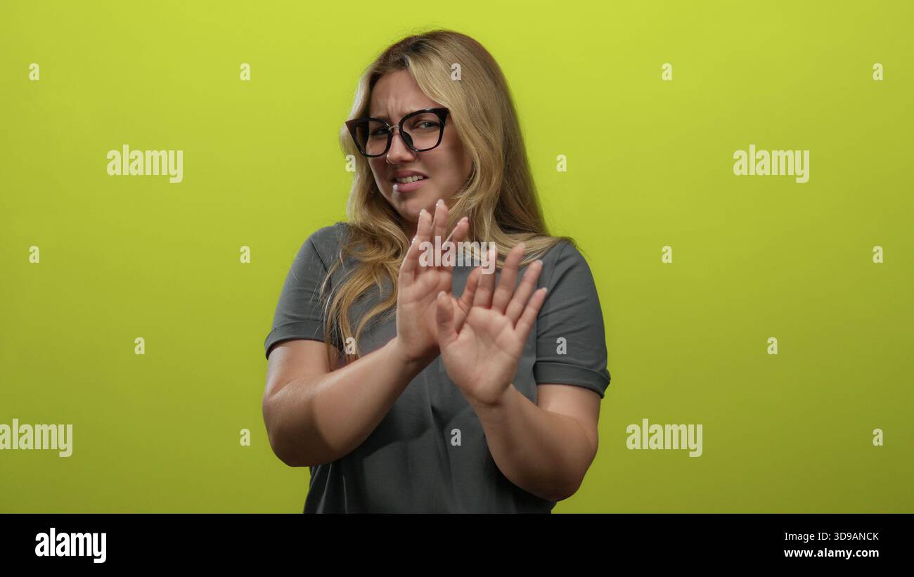 Woman expressing disgust with hands raised in front of isolated green ...