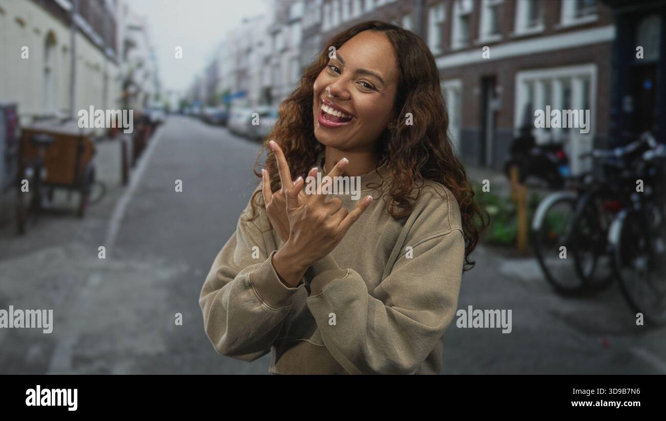 Young african american woman smiling with hands crossed making rock ...