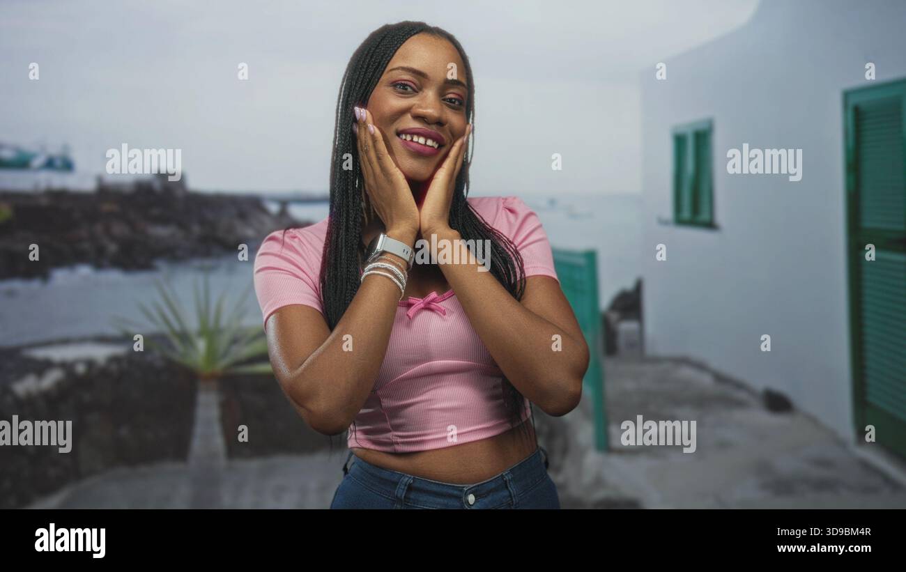 Woman cupping hands on cheeks, smiling in front of a white building ...