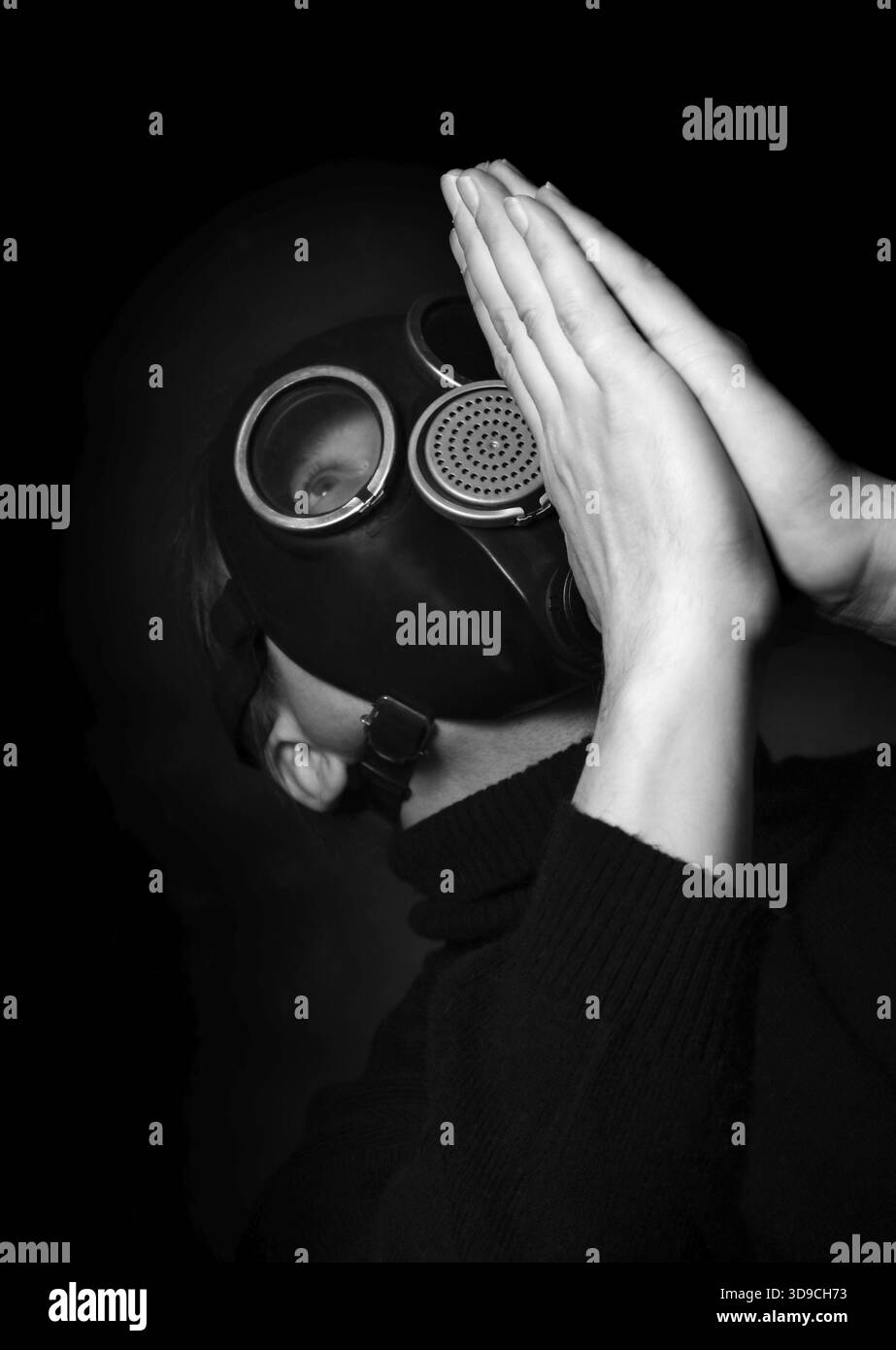 The man in a gas mask on a dark background. Hands are combined as at ...