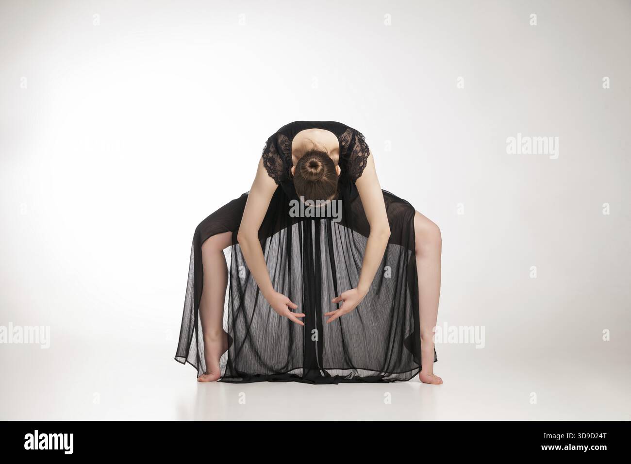 Young ballet dancer wearing black transparent dress dancing over white ...