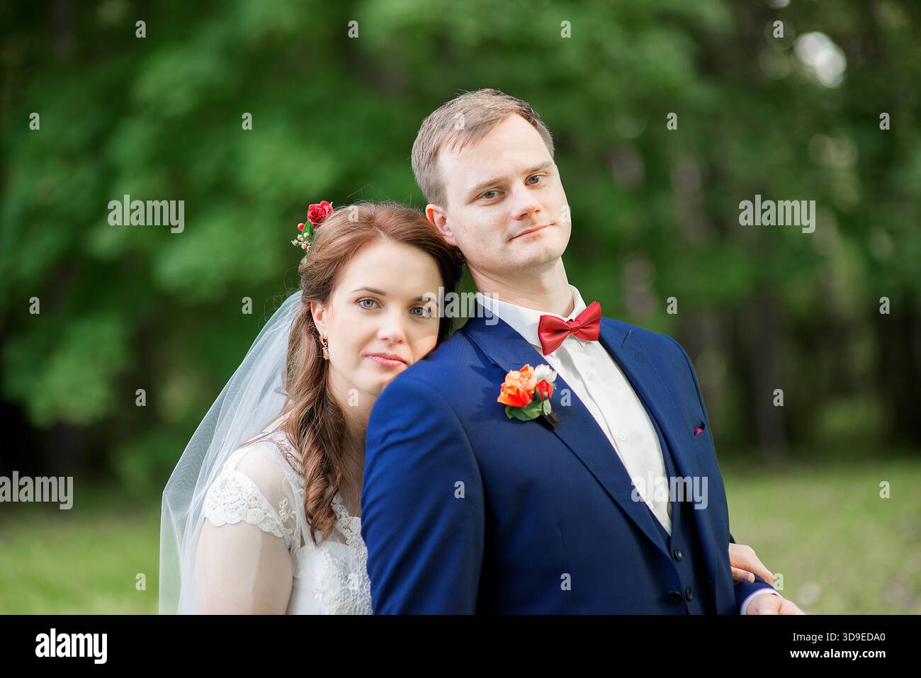 Young bride and groom standing together in lush green park with soft ...
