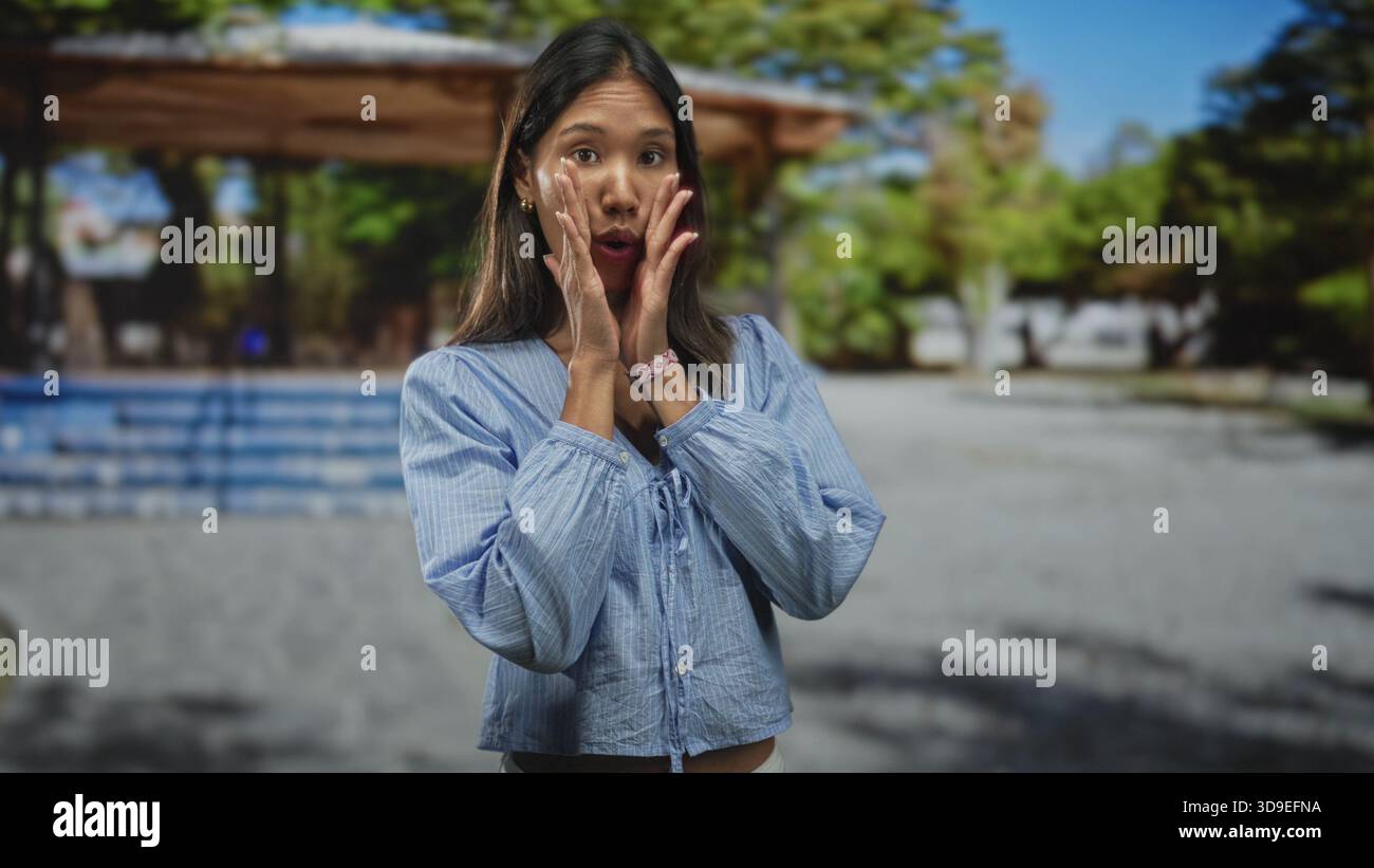 Young thai woman with hands on cheeks smiling and squinting, posing in ...