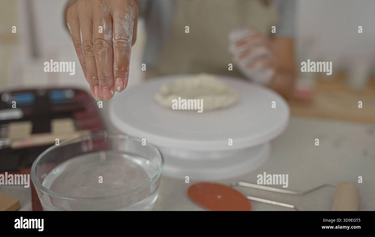 Woman artisan hand dipping floury fingers into a glass bowl beside ...