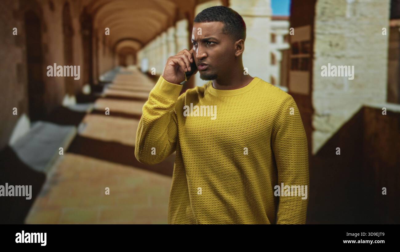 Young black man holds smartphone to ear with tense, puzzled expression ...