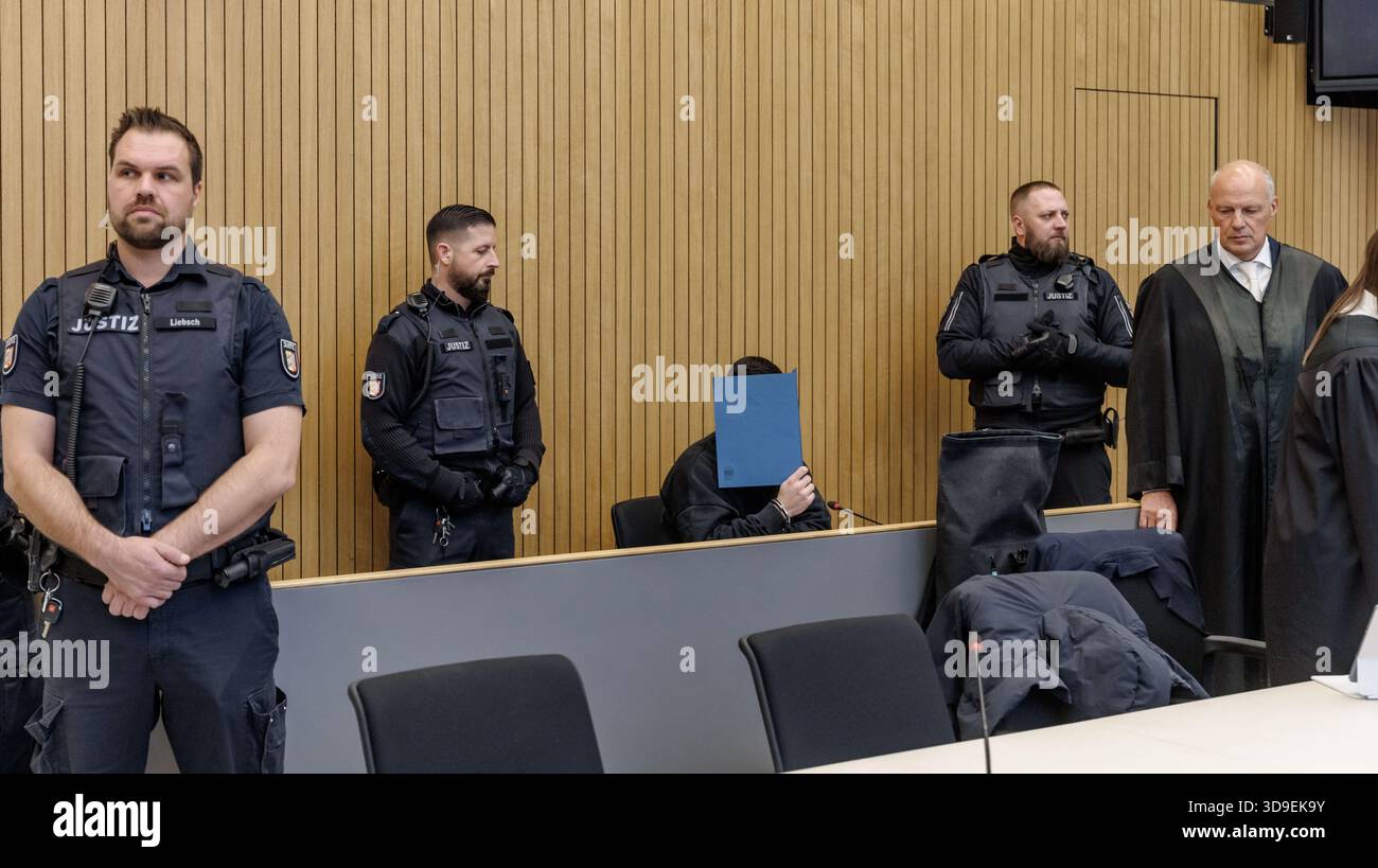 05 December 2025, Schleswig-Holstein, Lübeck: The defendant hides his ...