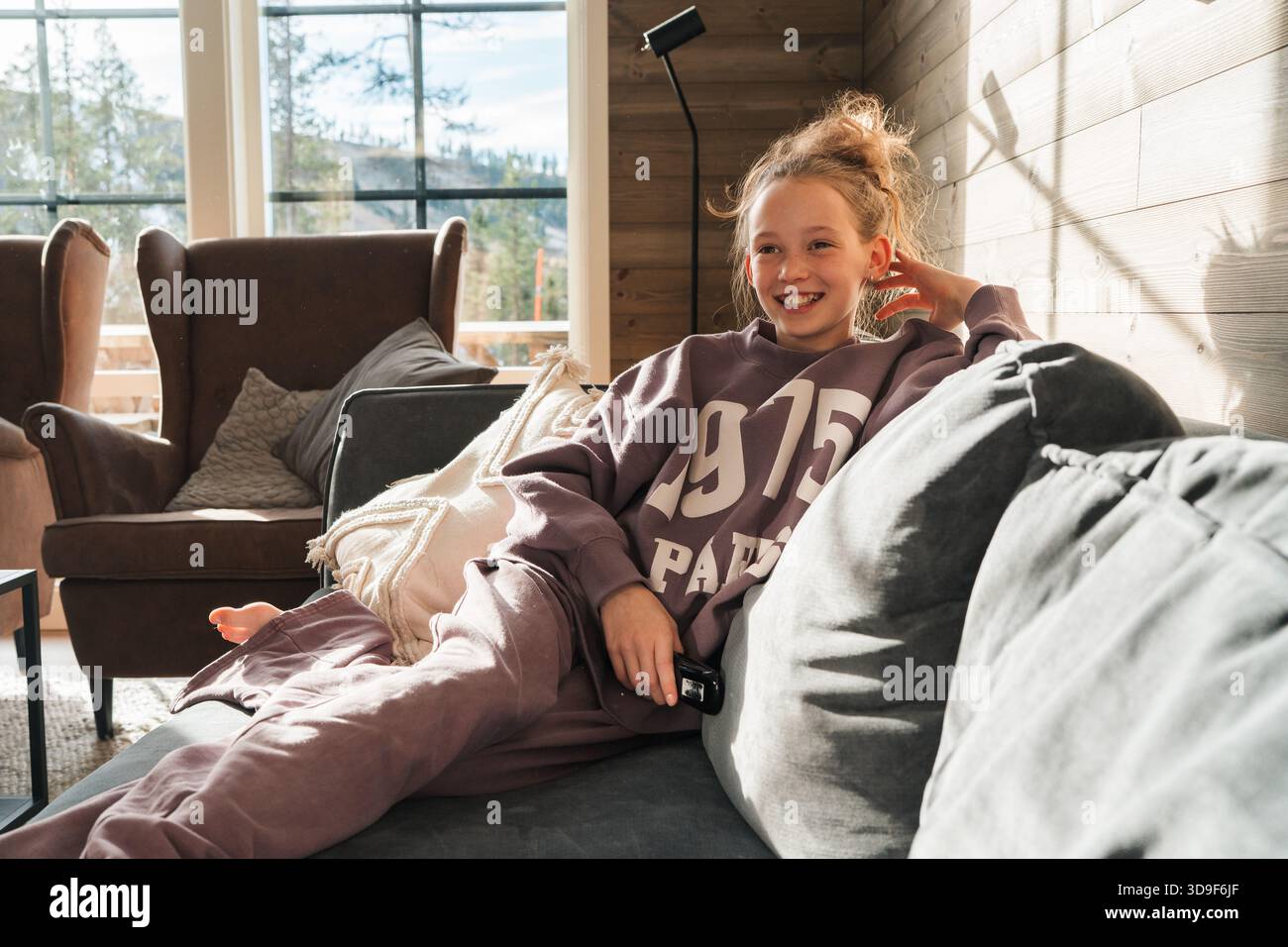 girl happily sat on the sofa at home watching TV Stock Photo - Alamy