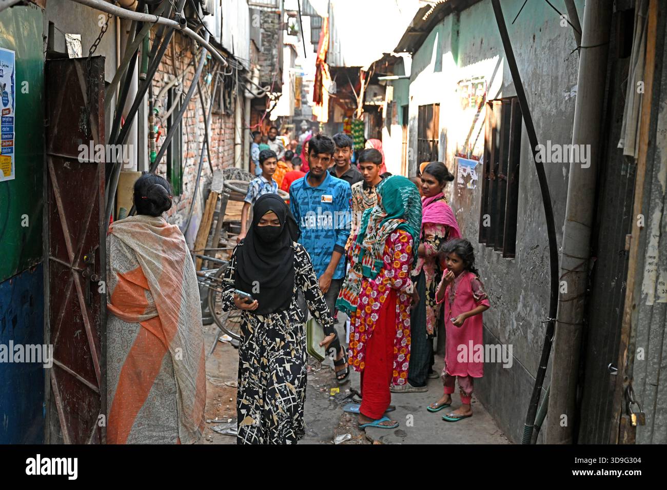 Slum dwellers are walking in the Korail slum in Dhaka, Bangladesh, on ...