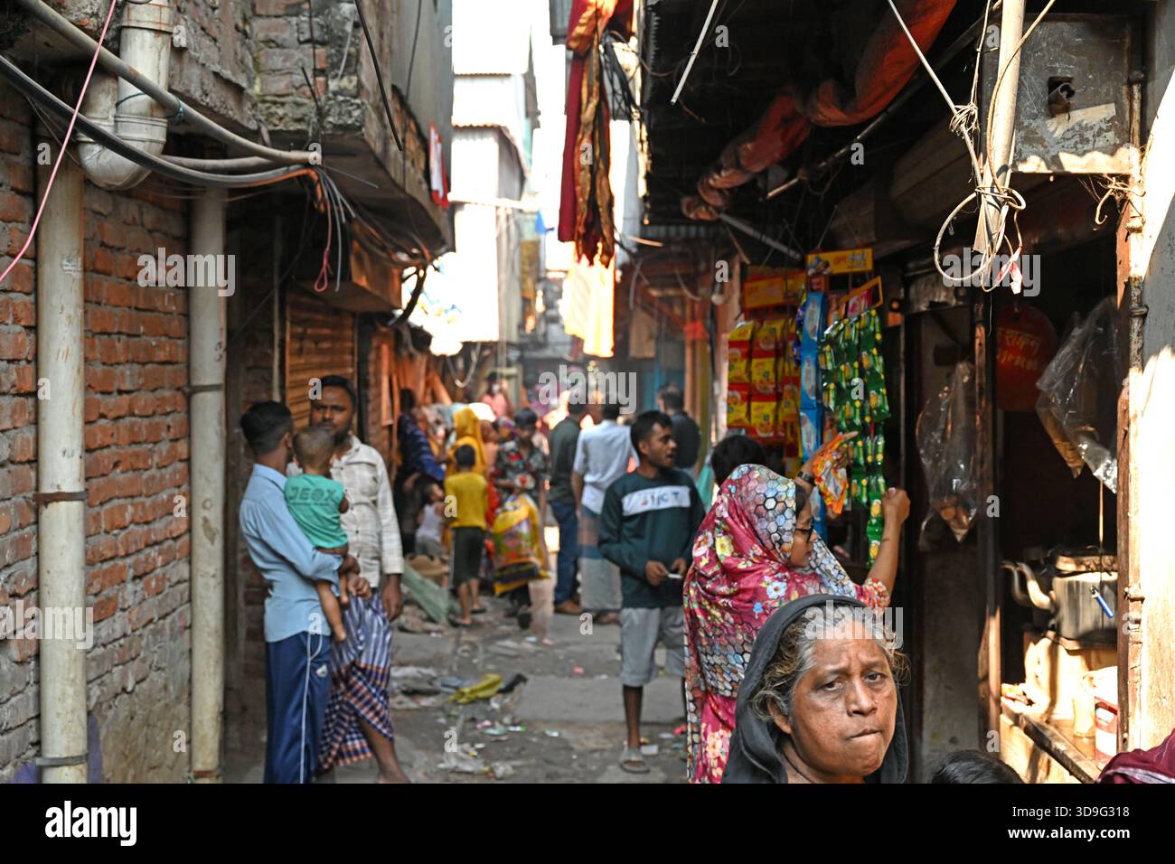 Slum dwellers are walking in the Korail slum in Dhaka, Bangladesh, on ...