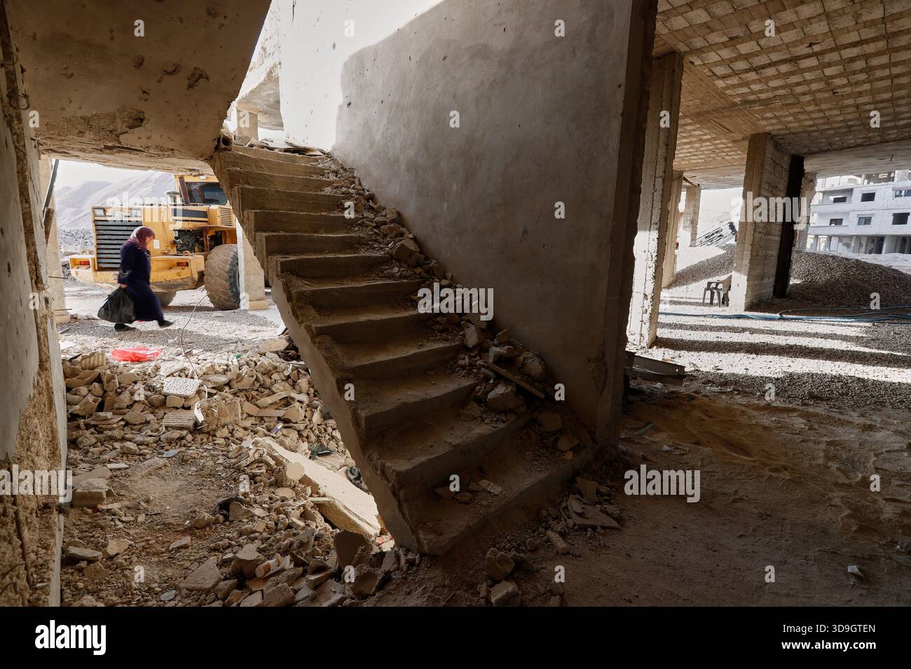 A woman walks by a war-damaged building in the Damascus suburb of ...
