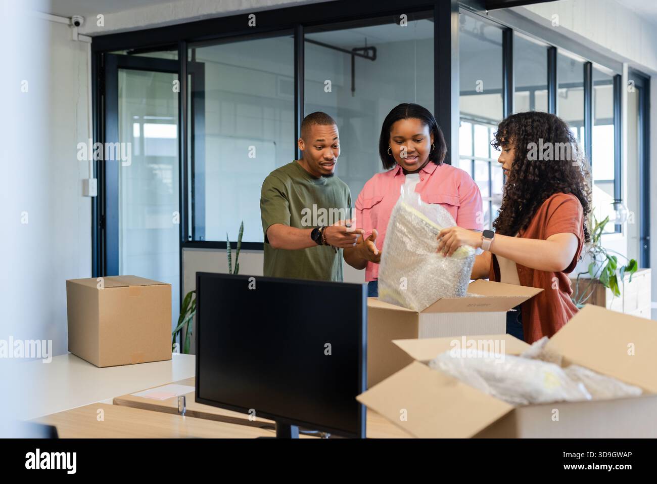 African American coworkers unpacking boxes and removing bubble wrap at ...