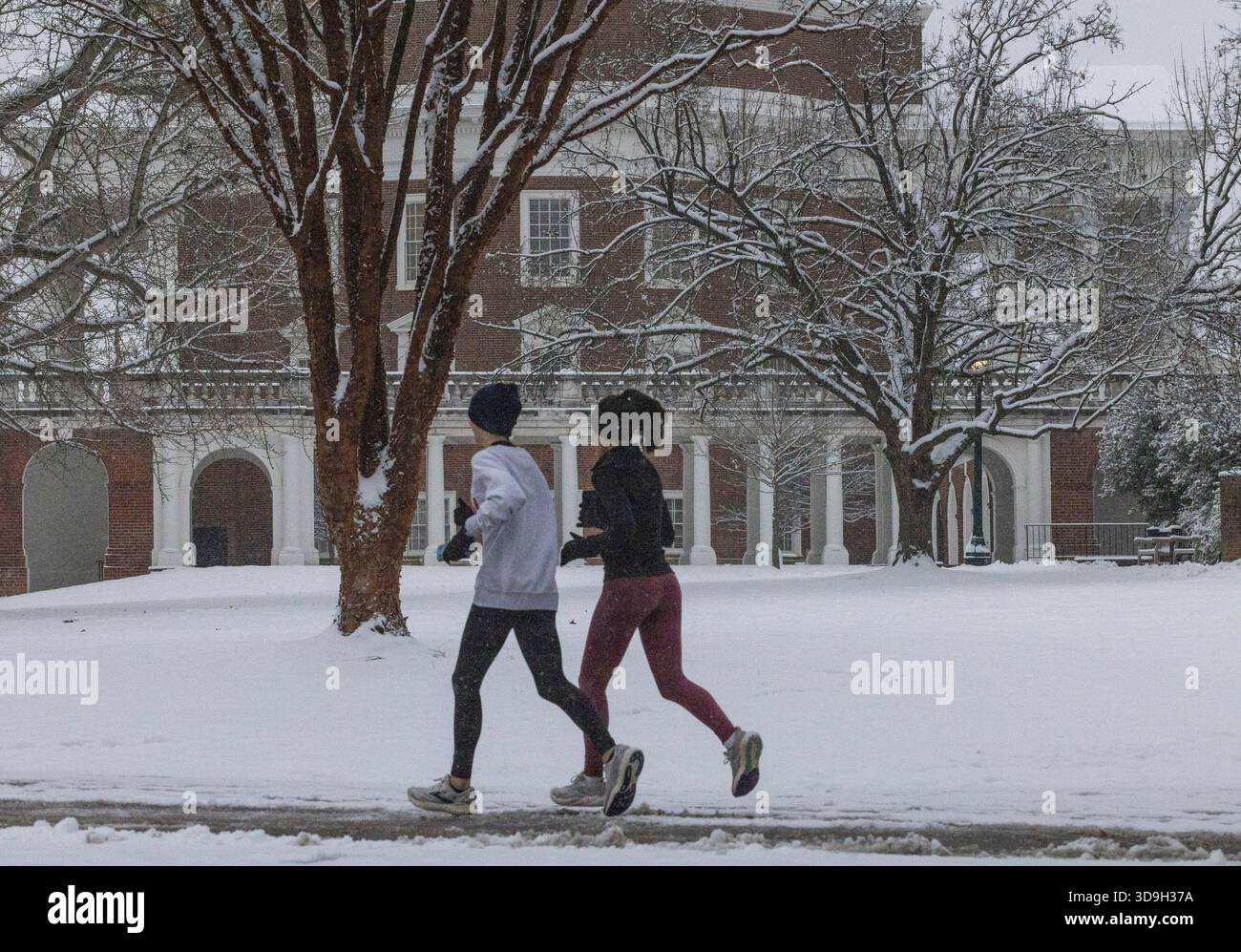 Two people go on a run by the Rotunda at The University of Virginia as ...