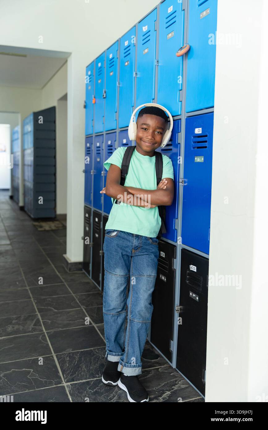 African boy child leaning against blue lockers in school hall wearing ...
