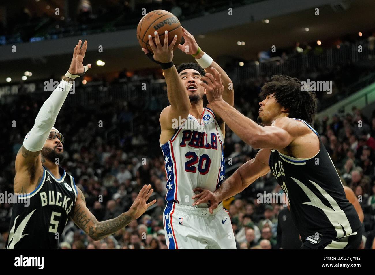 Philadelphia 76ers' Jared McCain (20) shoots between Milwaukee Bucks ...