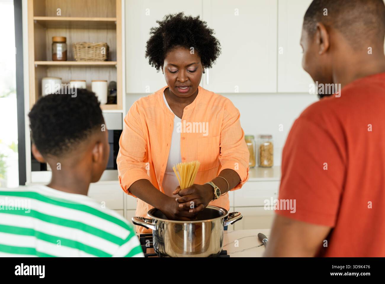 African American family cooking pasta at kitchen island with spaghetti ...