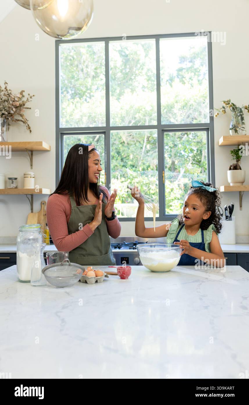 African American mother clapping while daughter whisking batter at ...