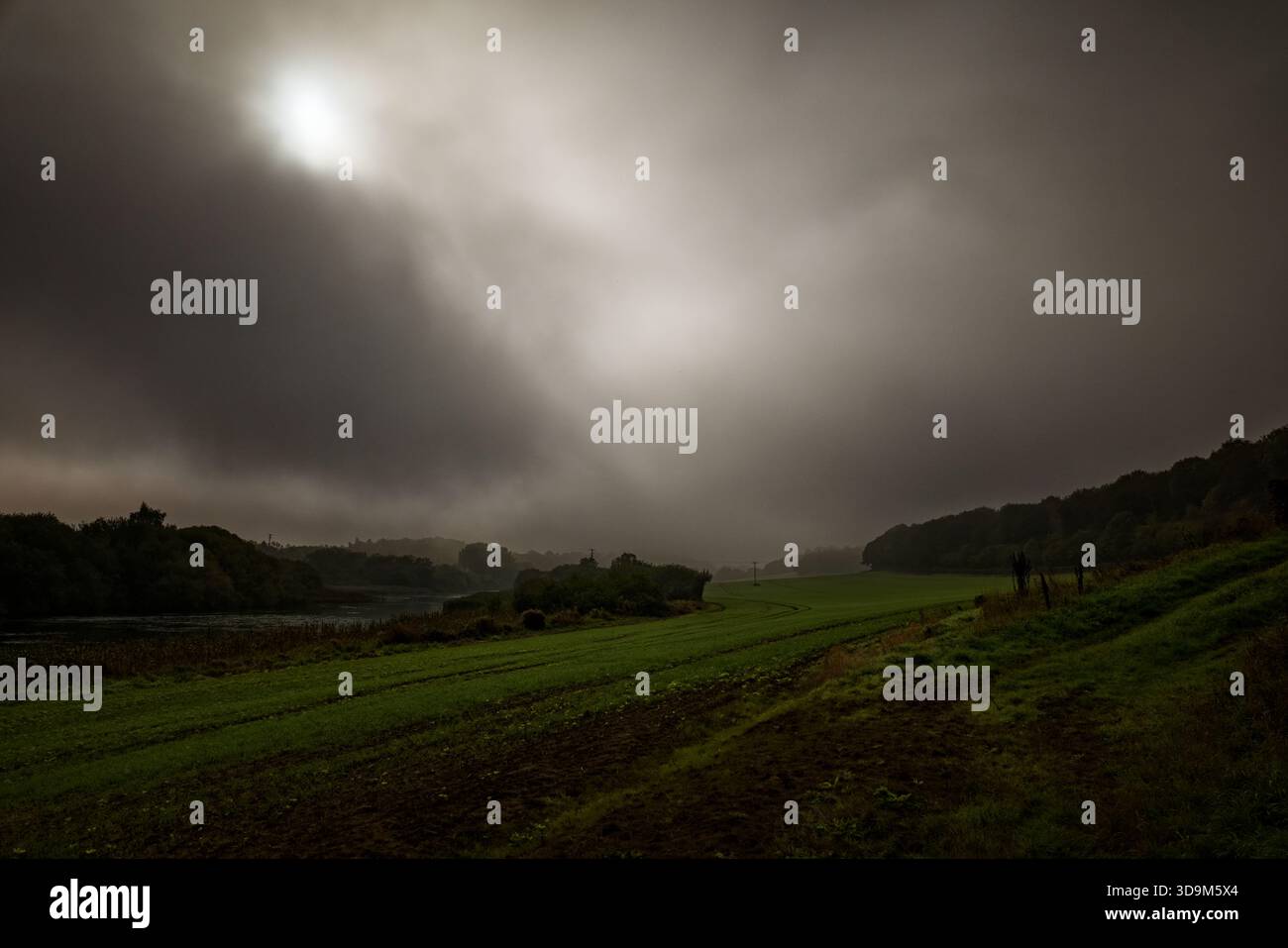 A shaft of sunlight bursts through thick misty clouds to shine on an ...