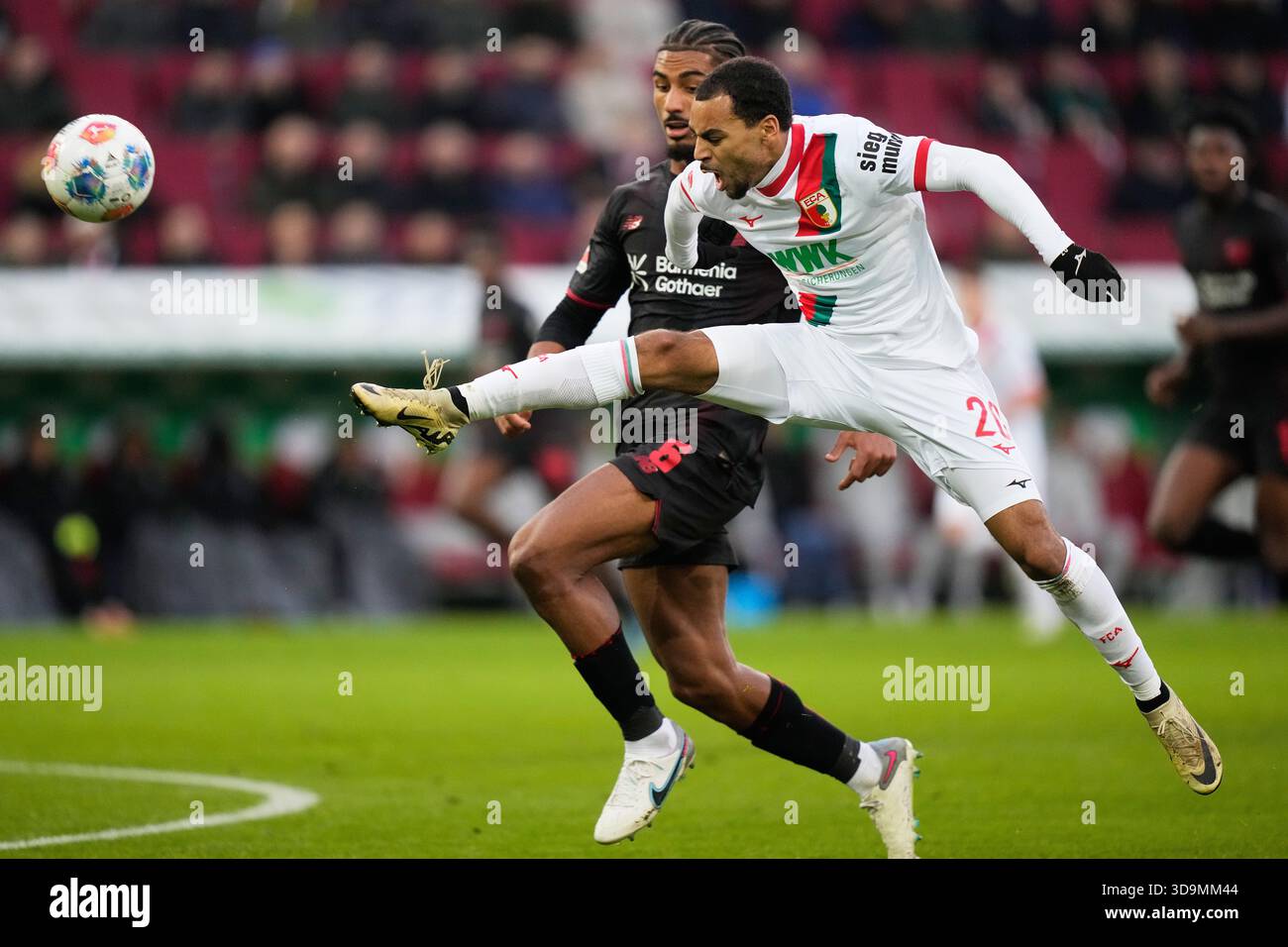Augsburg's Alexis Claude-Maurice, foreground, tries to score ...