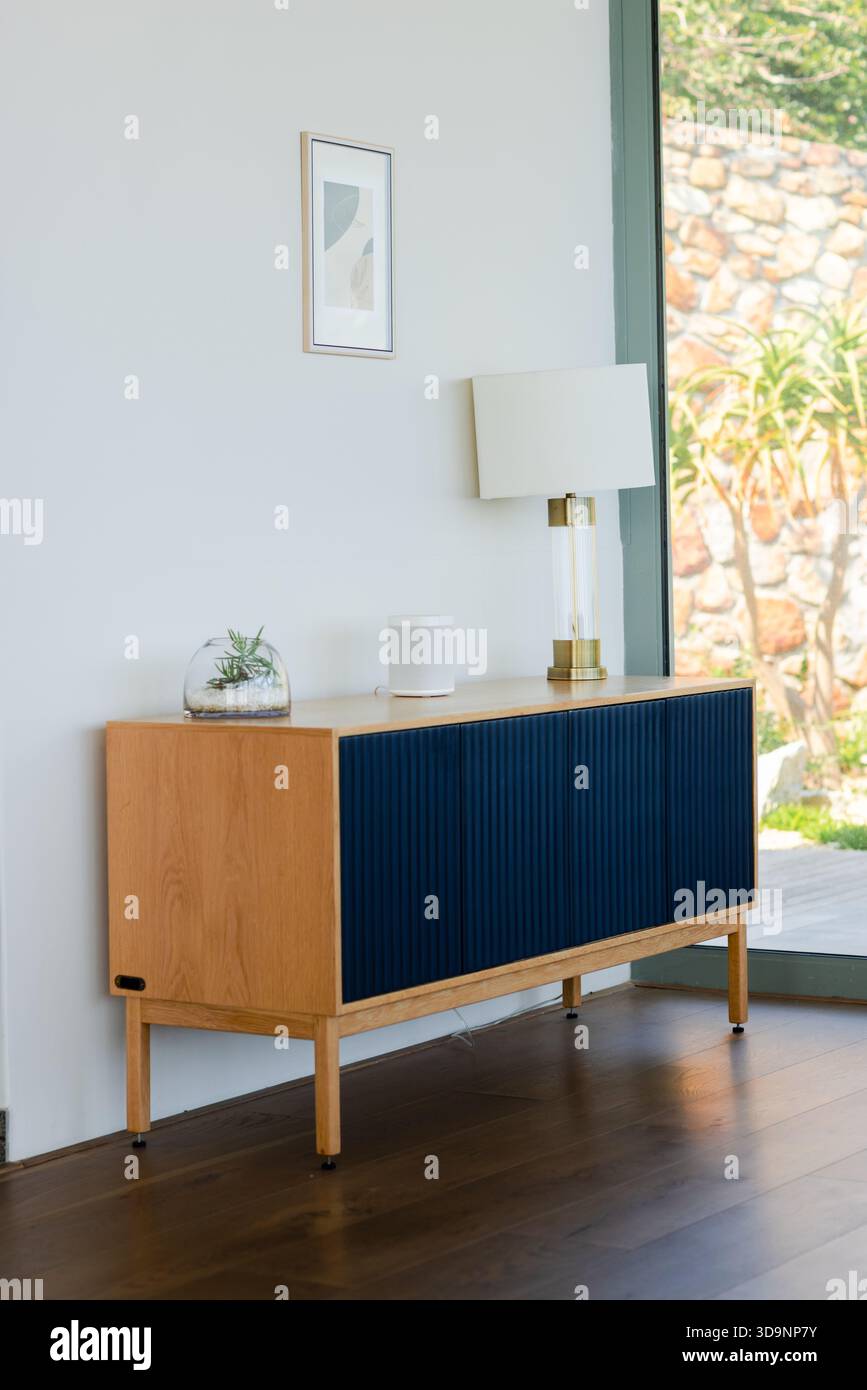 Navy blue ribbed sideboard standing in living area holding glass ...