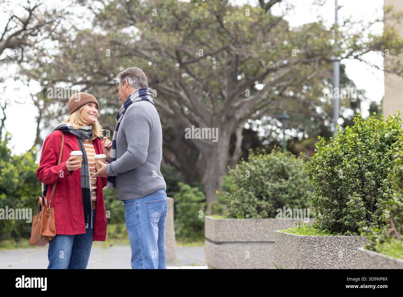 Senior couple talking and sipping to-go coffee cups standing in ...
