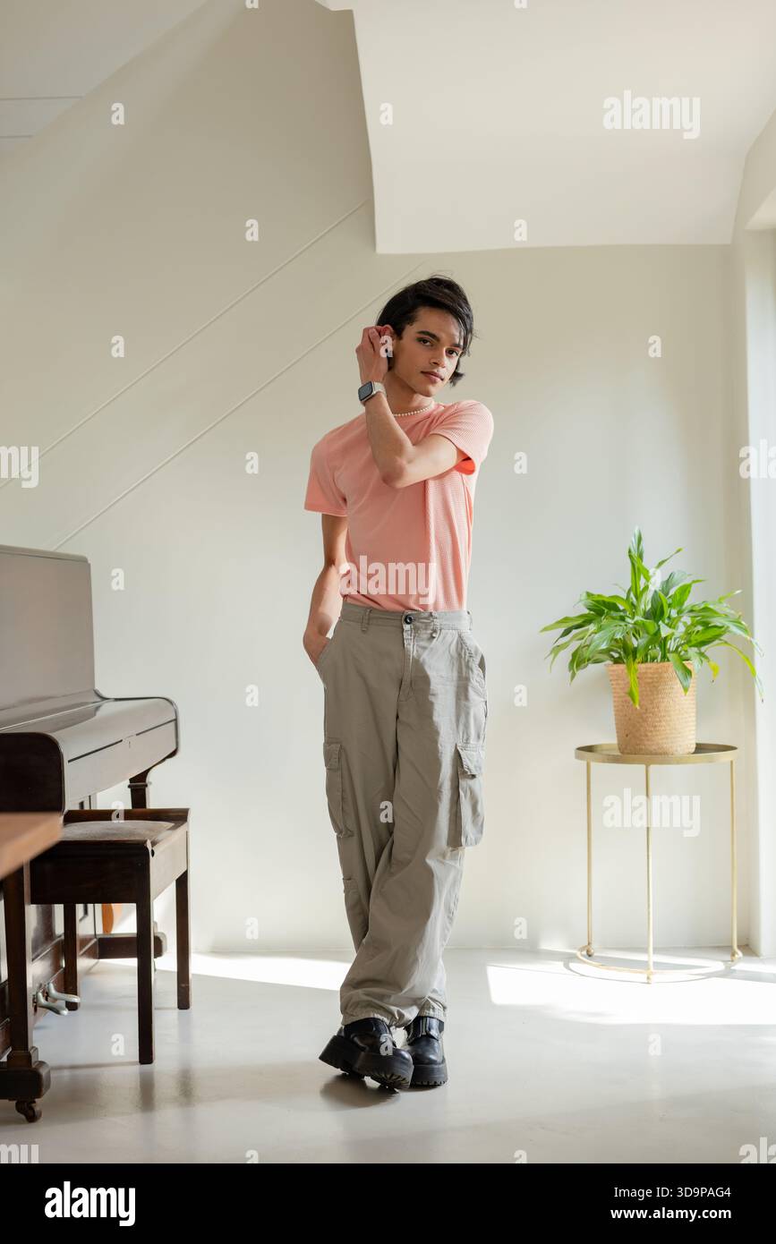 Asian man standing beside upright piano bench checking smartwatch at ...