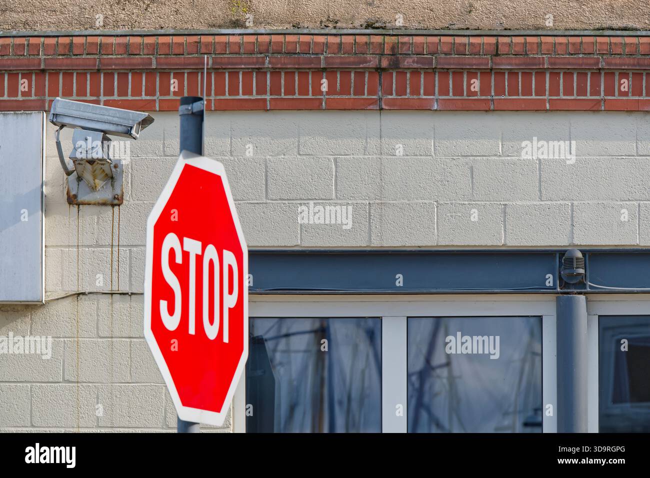 A stop sign in front of a building with a security camera mounted on ...