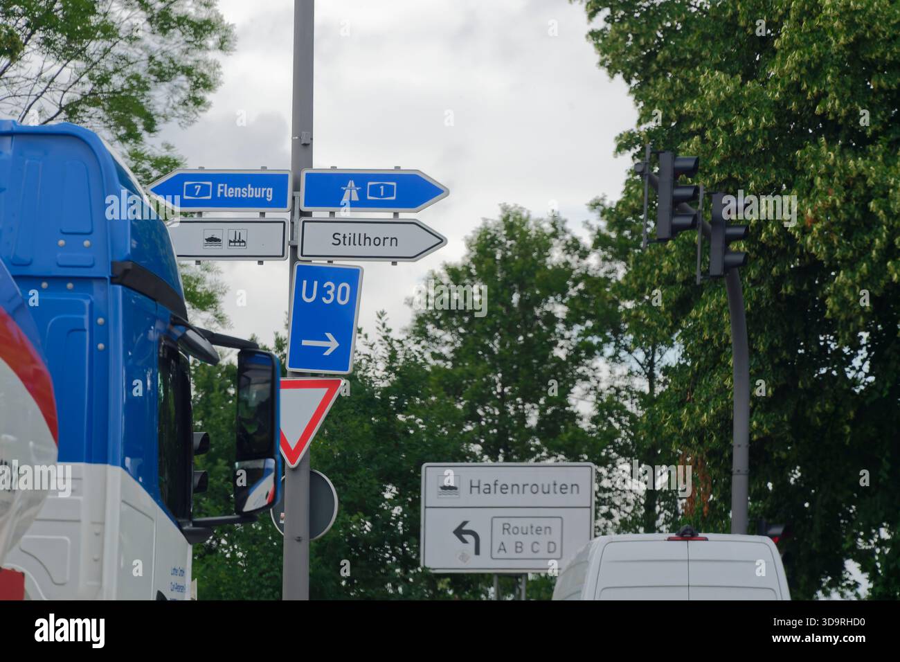 A truck drives past several German road signs including yield, route ...