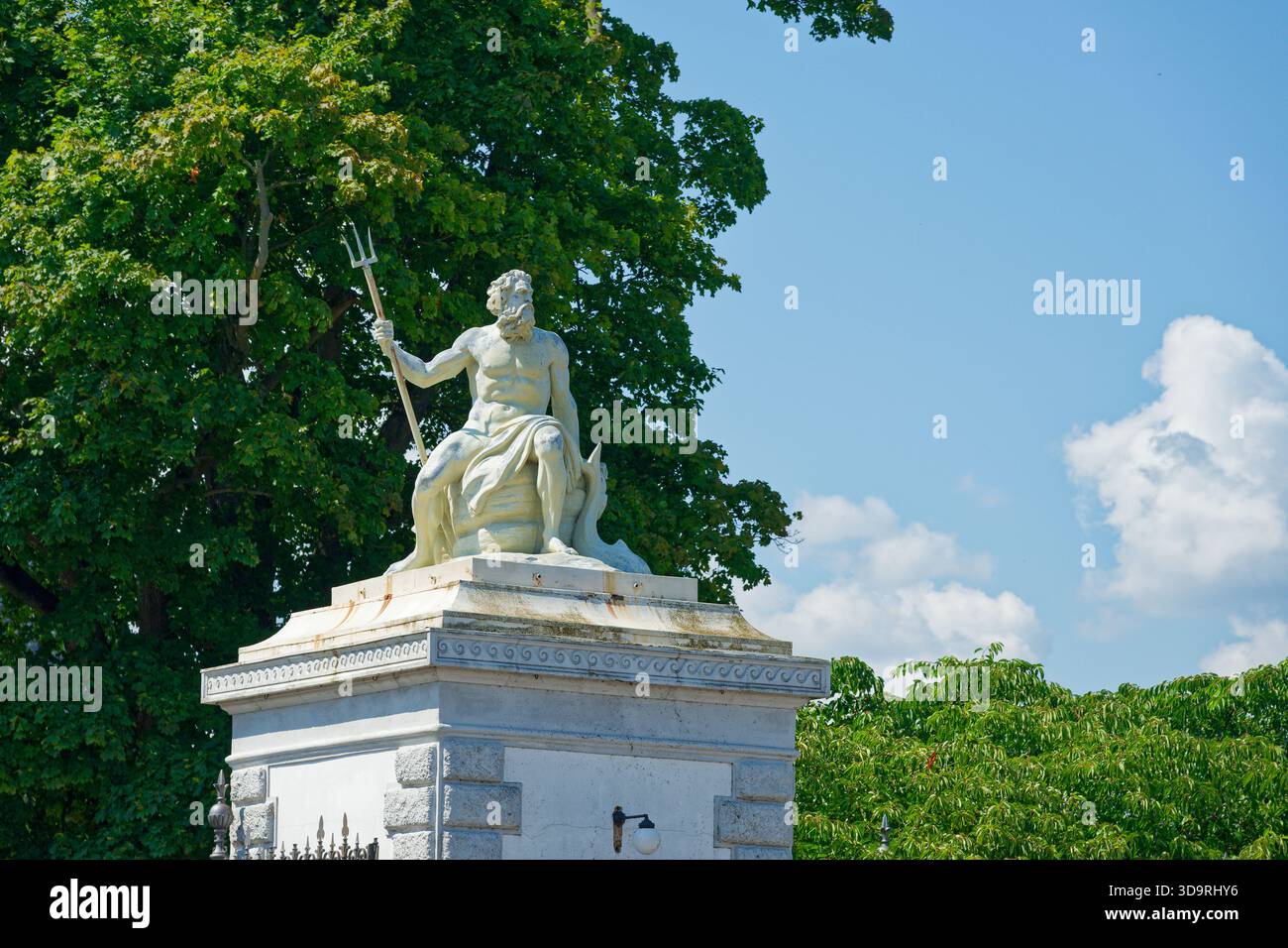 A white stone statue of Neptune sits majestically on rocks, holding his ...