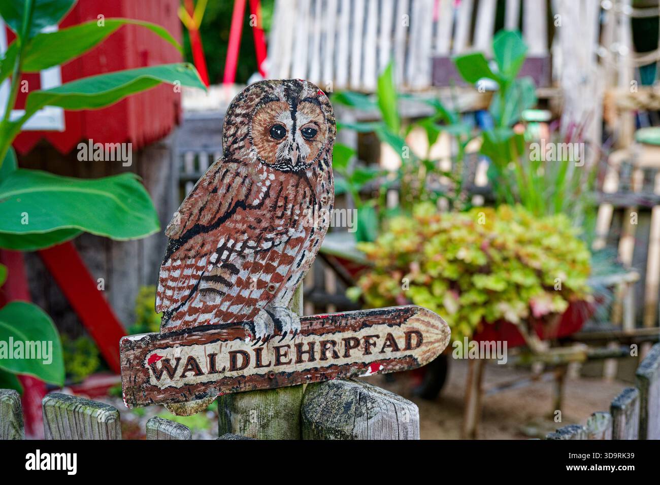A painted wooden owl decorates an old fence with an arrow pointing ...