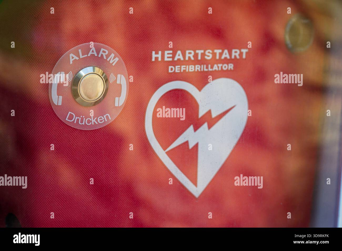 A bright red wall mounted heart start defibrillator box with a clear ...
