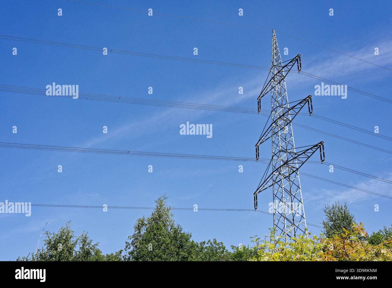 A tall electric power pole stands with three distinct rows of cables ...