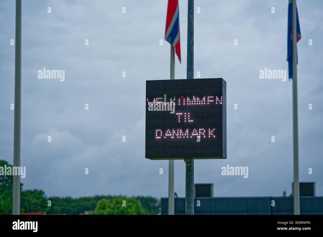 A metal post displays a screen with the message Velkommen til Danmark ...