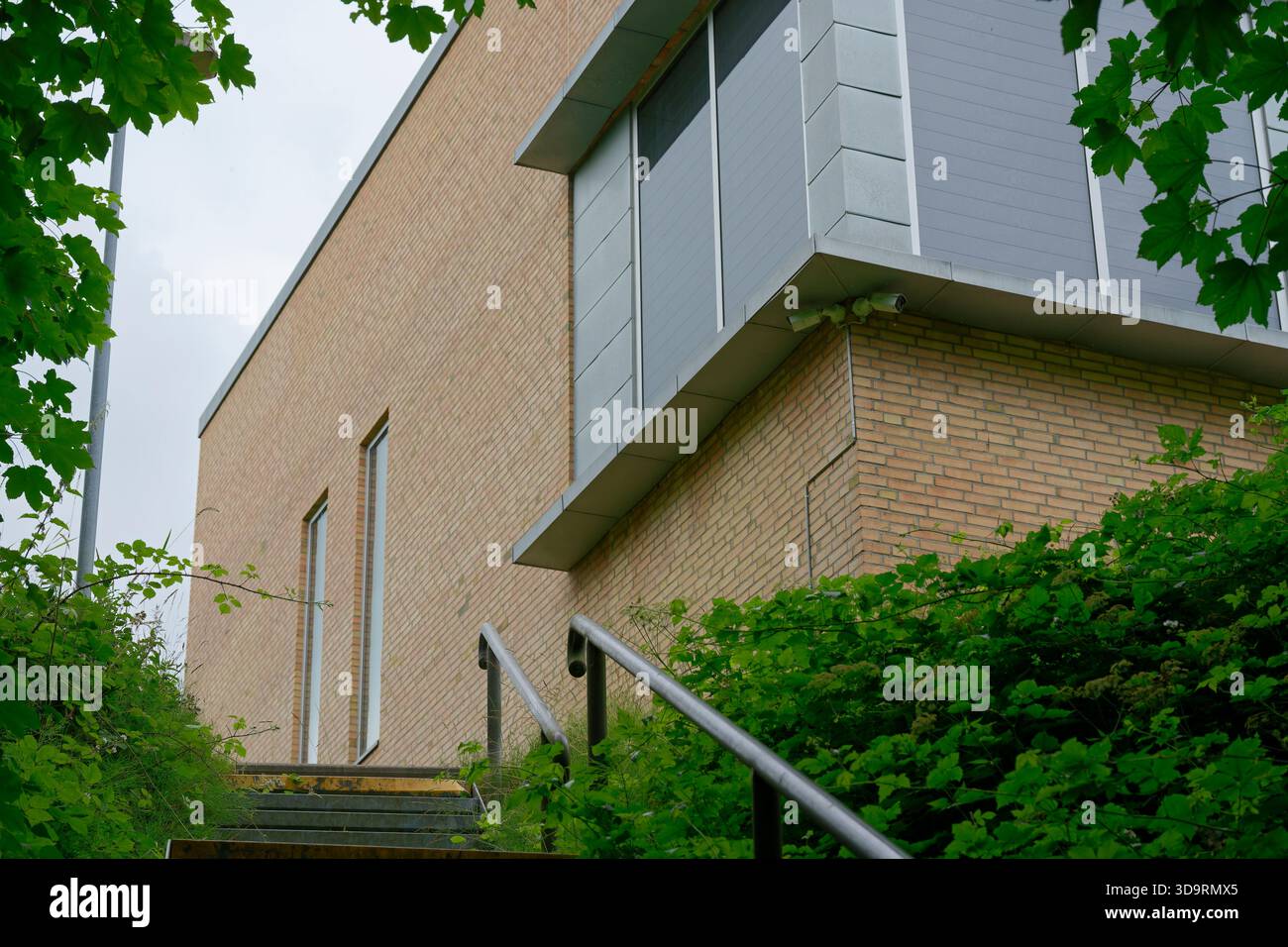 A beige brick facade forms a sharp corner with wide panoramic windows ...