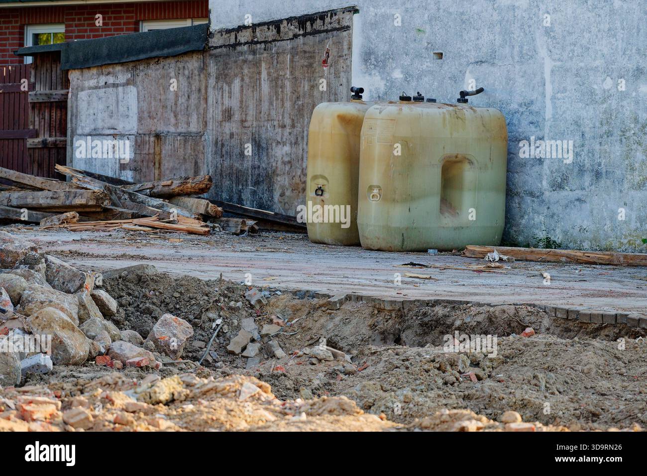 Two large canisters stand by a concrete wall in a torn up area. Broken ...