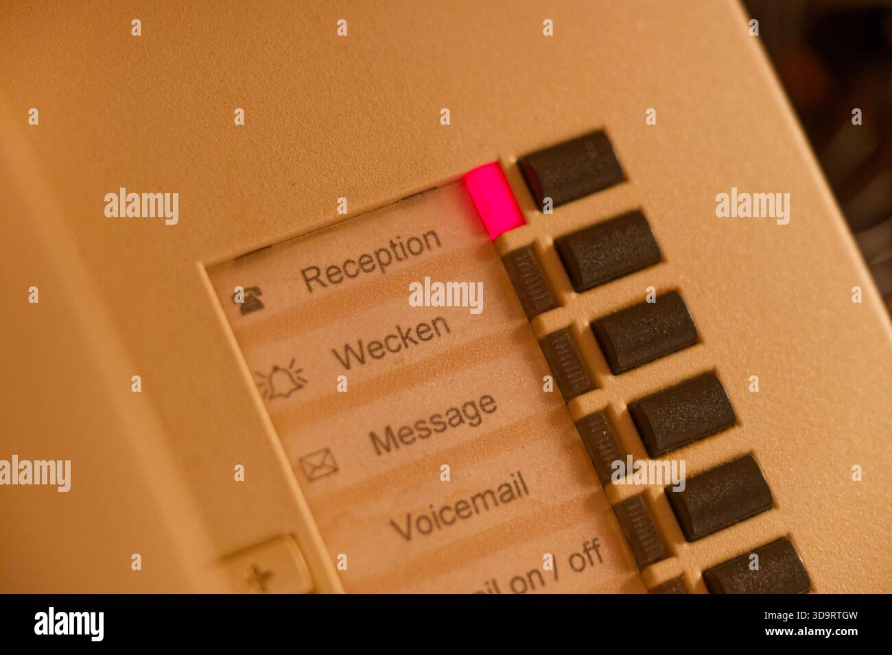 Closeup of a hotel room telephone with a glowing reception button and ...