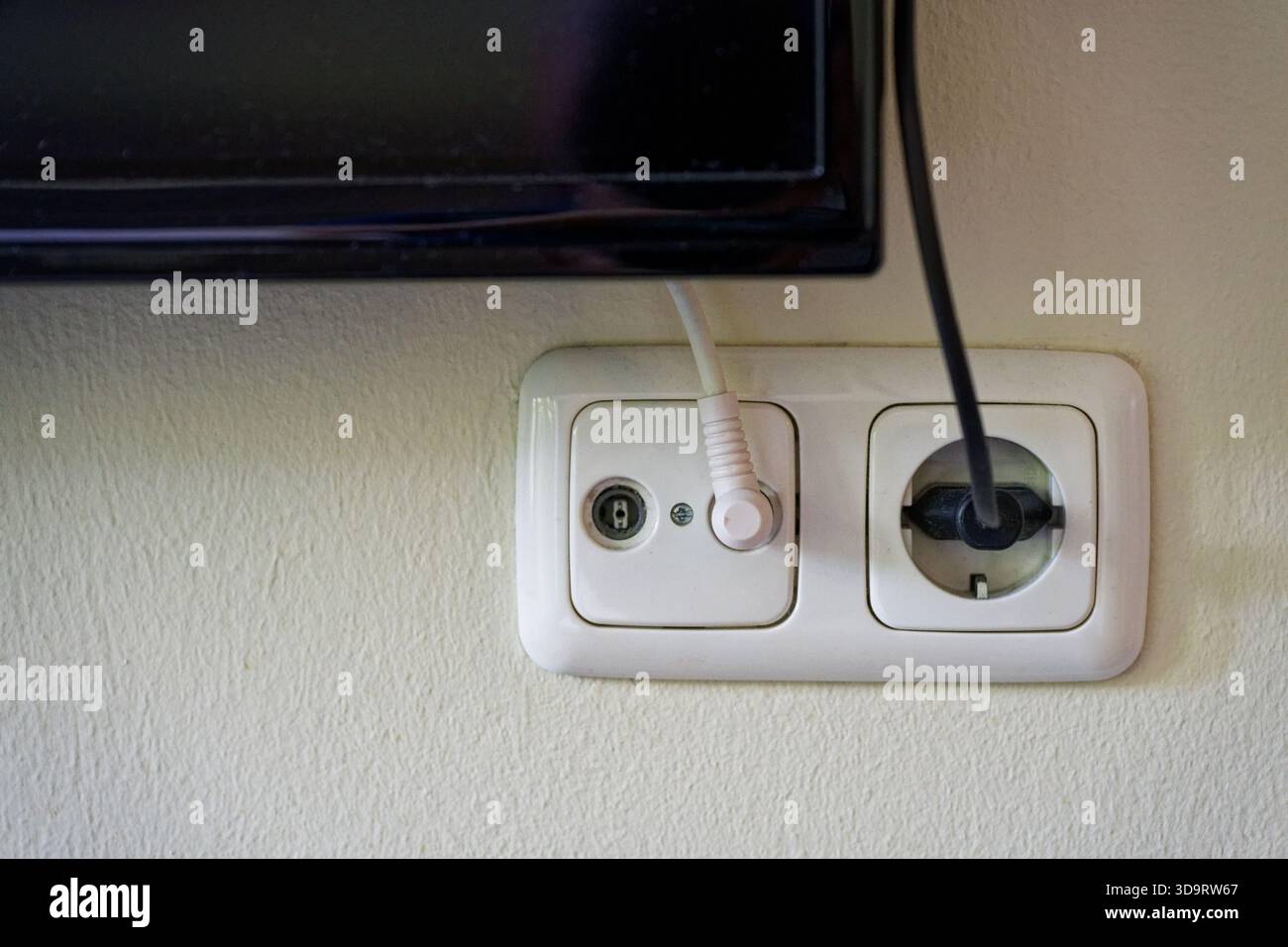 A wall screen hangs in the same area with all cords connected to outlet ...