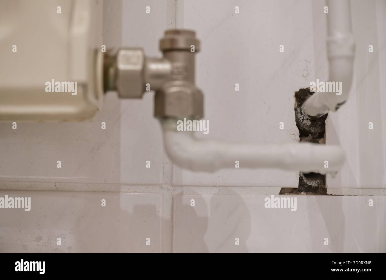 Close-up of plumbing pipes and fittings, showing a valve and a wall ...