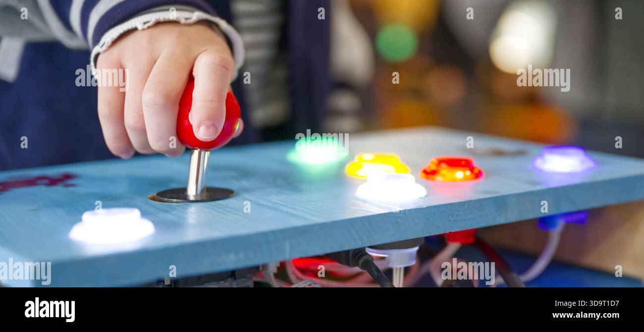 A child's hand playing with a colorful joystick on a light-up control ...