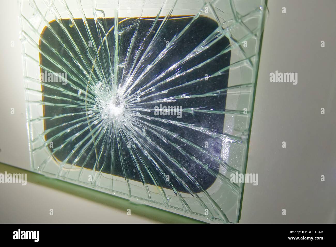 A close-up view of a shattered glass panel with a starburst pattern ...
