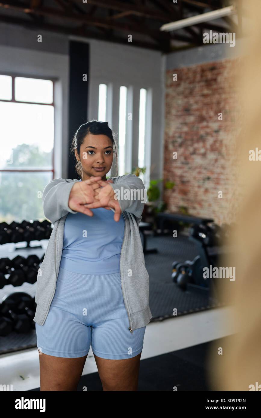 African American woman stretching arms forward in fitness studio with ...