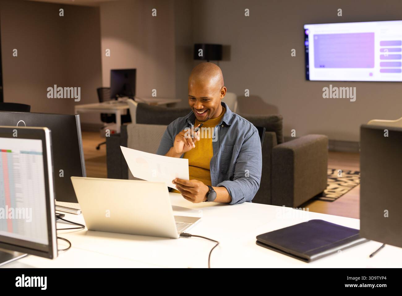 African American man reviewing document at office desk while viewing ...