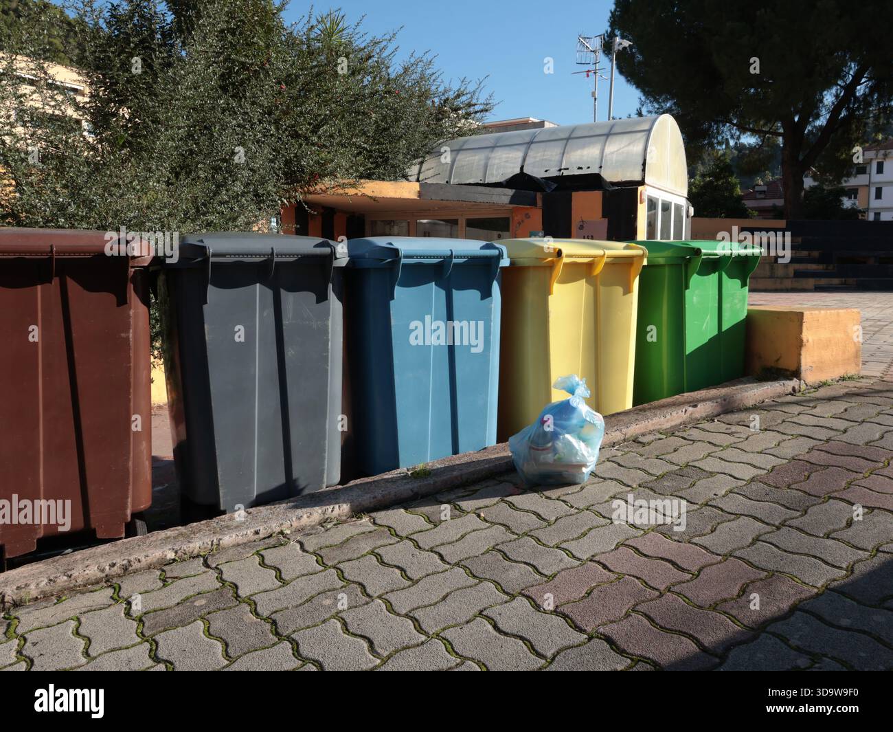 Plastic trash bag filled with trash in front of different colored trash ...