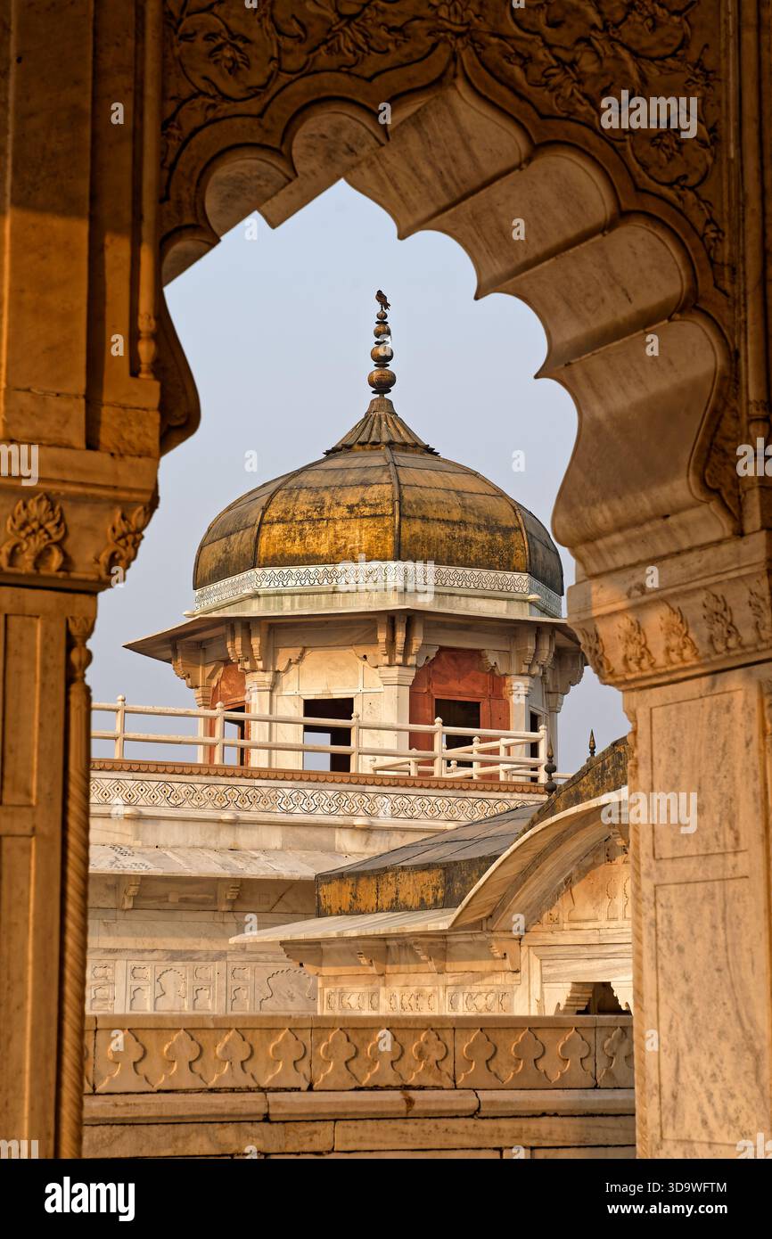 A domed tower of Agra’s Red Fort seen through an ornate arch at golden ...