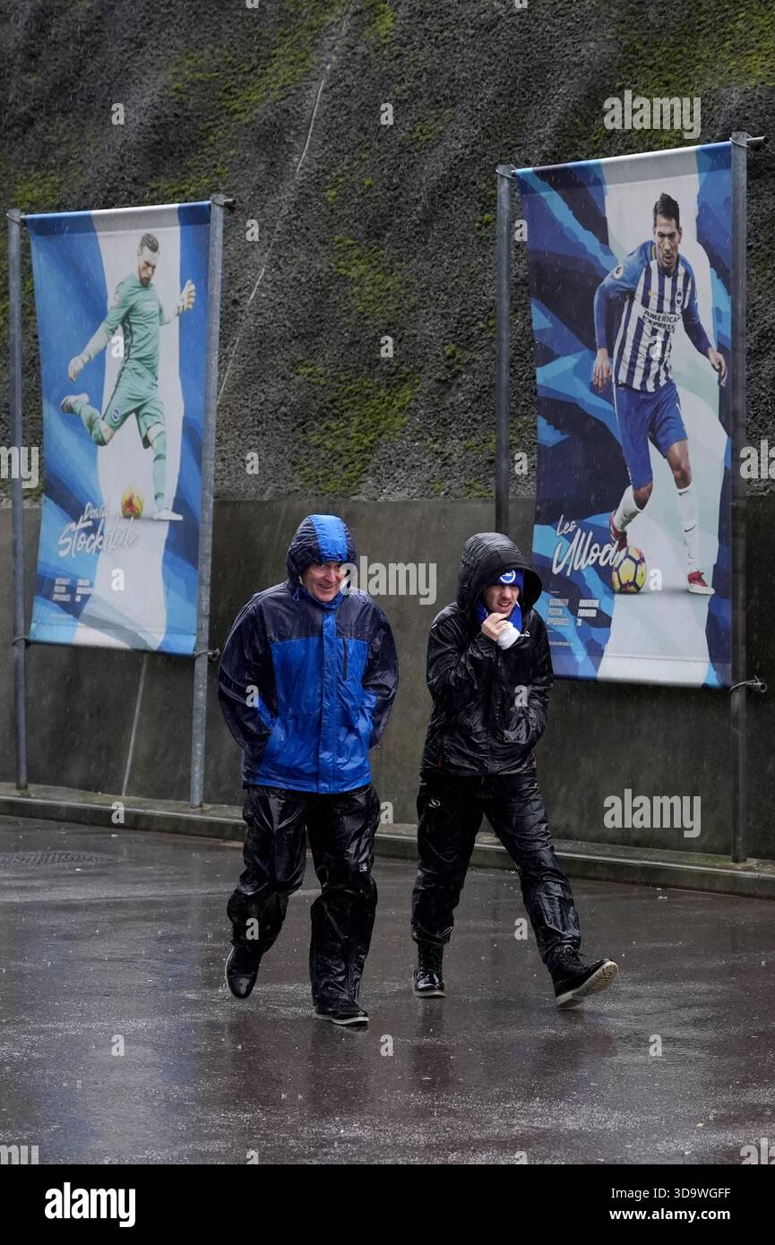 Fans walk in the rain as they arrive at the ground ahead of the Premier ...