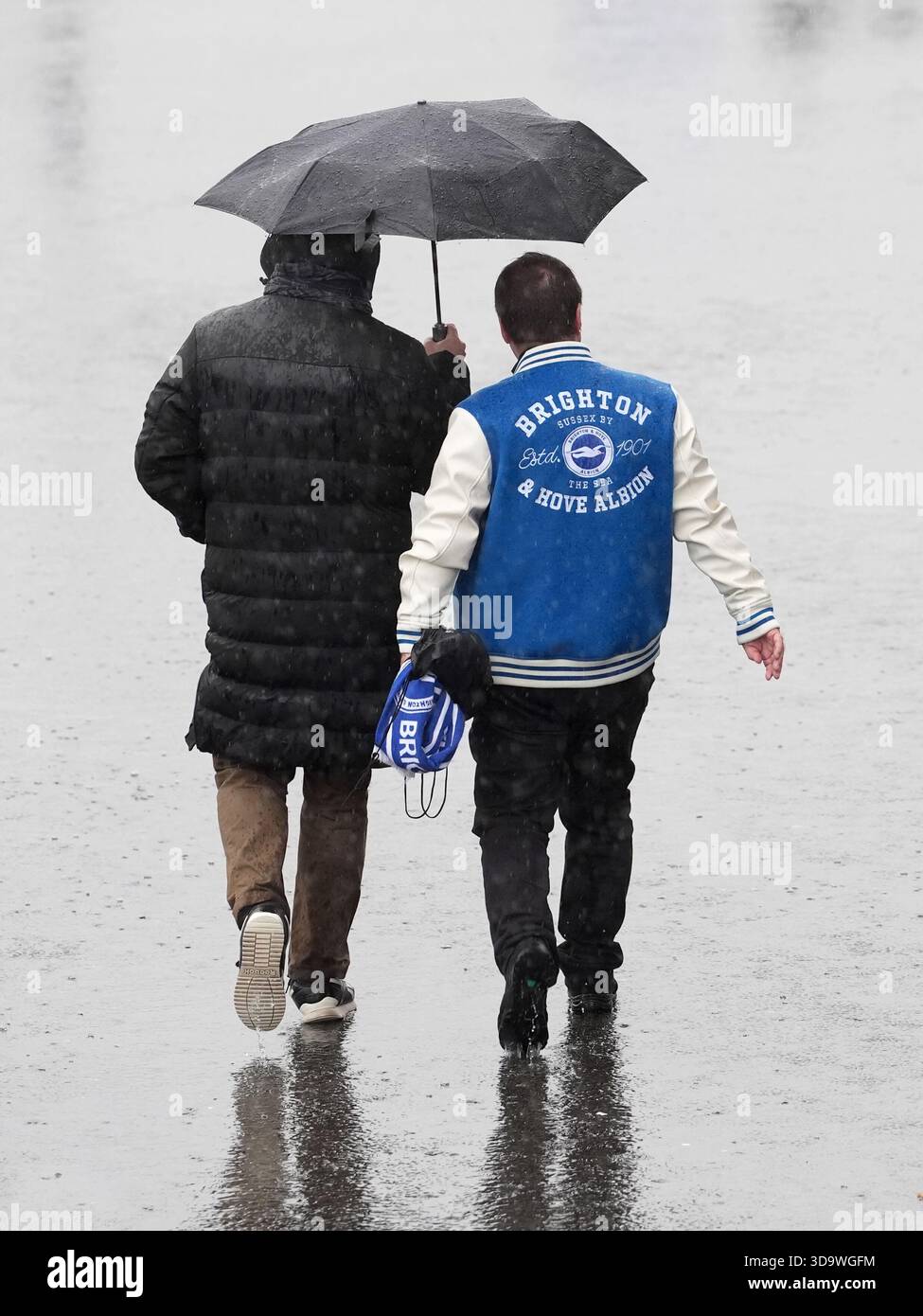 Fans walk in the rain as they arrive at the ground ahead of the Premier ...