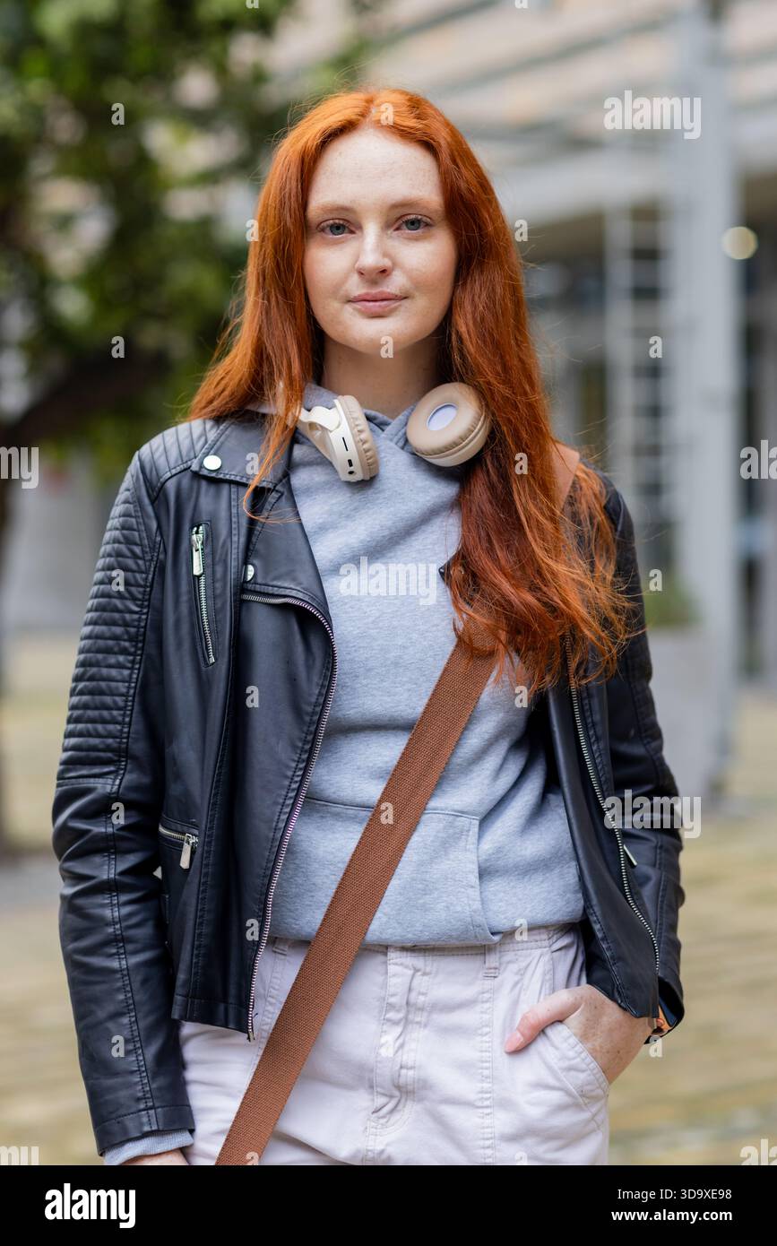 Female in her 20s standing on campus walkway wearing leather jacket ...