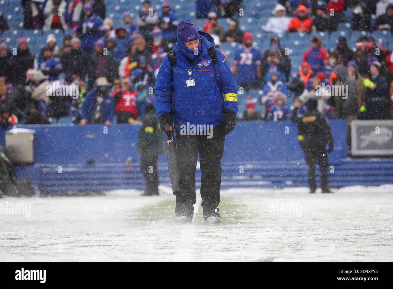 A worker blows snow from the field before an NFL football game between ...